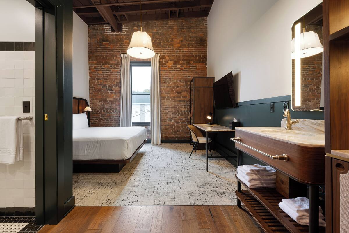 Quarto de hotel com cama, escrivaninha e toucador.