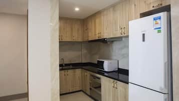 Cozinha com armários de madeira, geladeira branca, micro-ondas e lava-louças.
