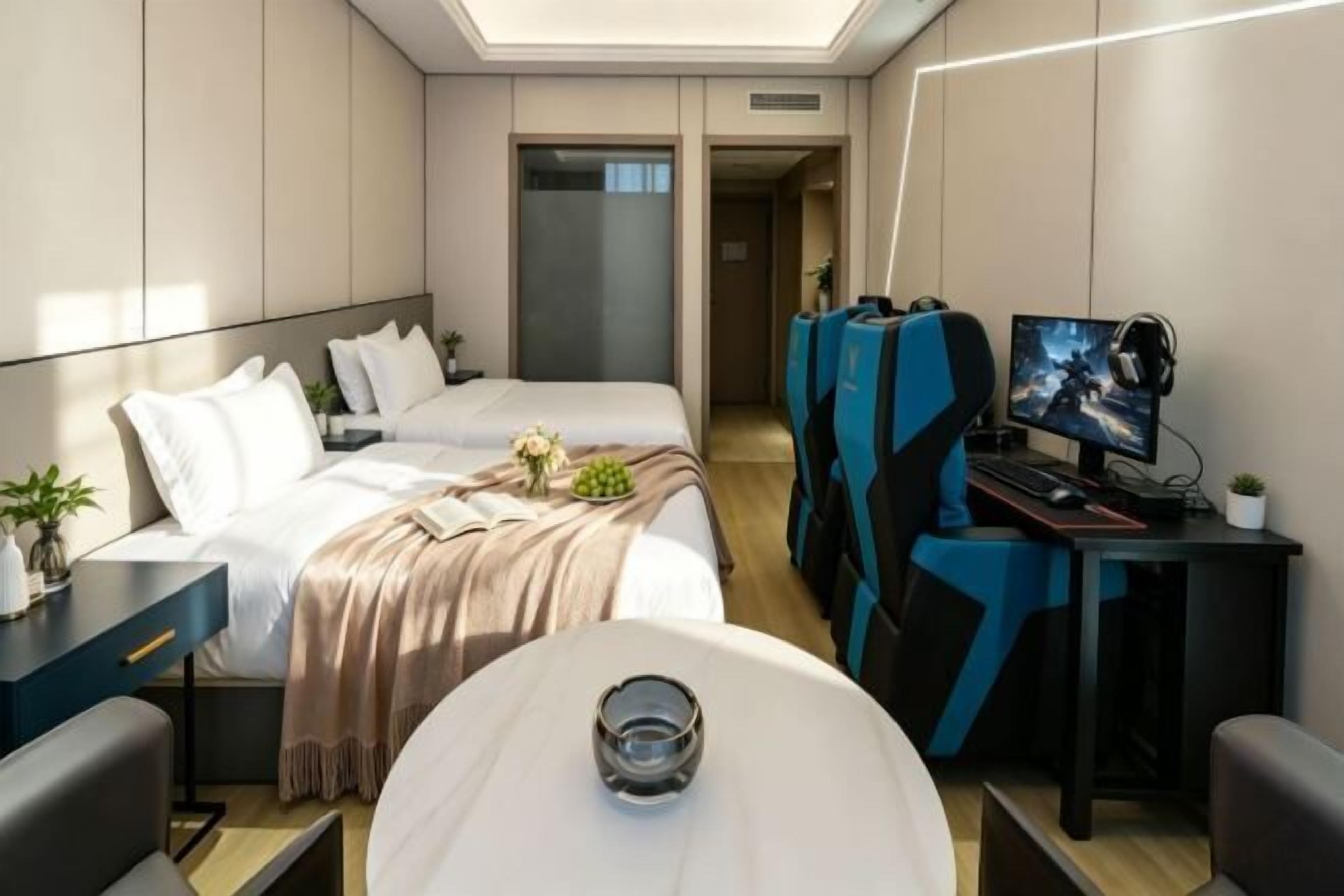 Quarto de hotel com cama, escrivaninha, cadeira e televisão.