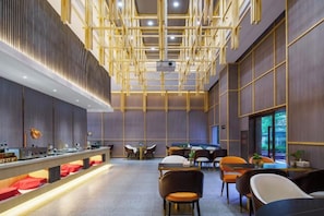 Restaurante moderno com teto alto, iluminação pendente e um balcão central.