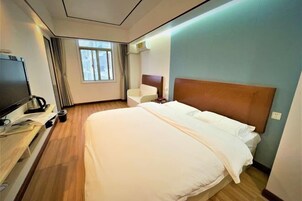 Quarto de hotel com cama, televisão, secretária e janela.