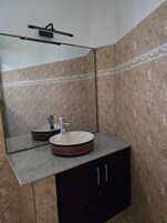 Uma casa de banho com uma pia redonda, um espelho e um armário.