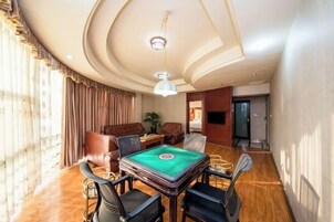 Quarto com mesa de bilhar, poltronas de couro, sofá e luminária no teto.