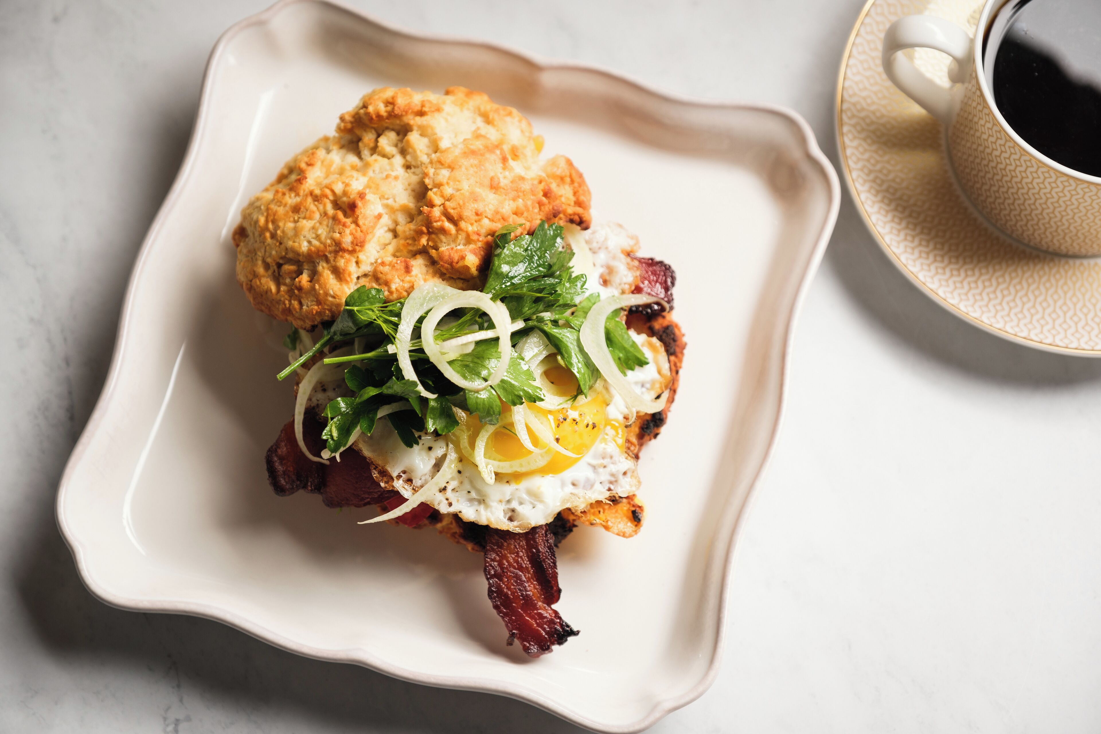 Prato de café da manhã com bacon, ovo e vegetais sobre um prato branco.