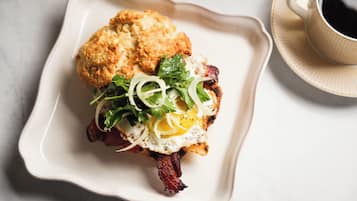 Prato de café da manhã com bacon, ovo e vegetais sobre um prato branco.