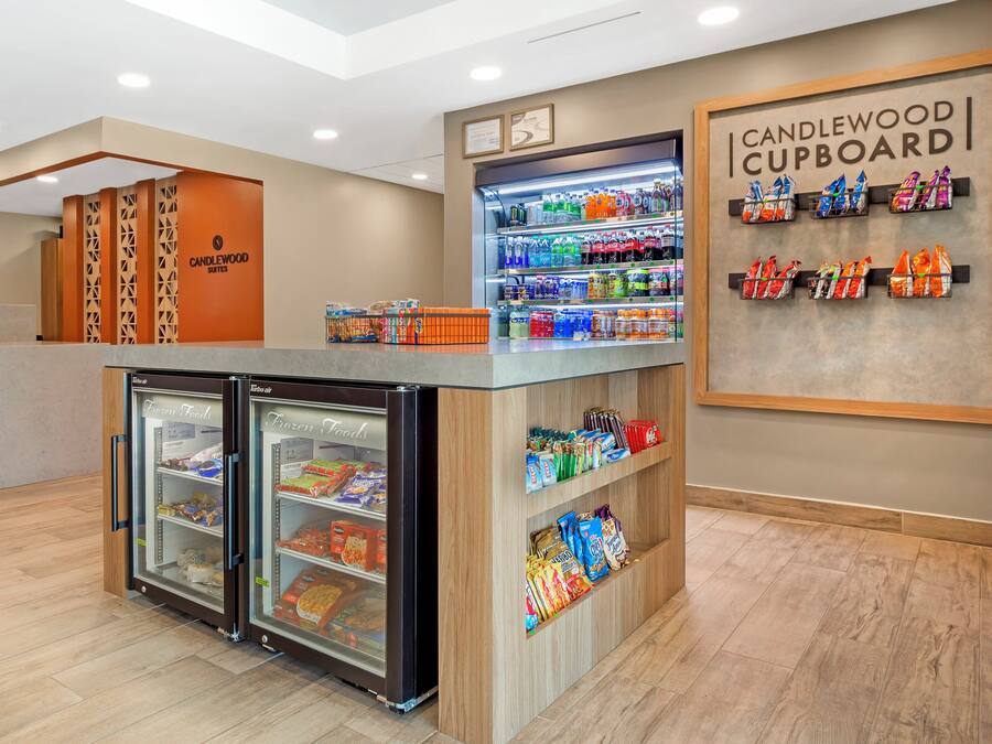 Área de recepção de hotel com um refrigerador, um freezer e um aviso na parede para o Candlewood Cupboard.