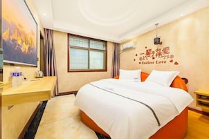 Quarto de hotel com cama, escrivaninha, cadeira, janela e um ornamento na parede.