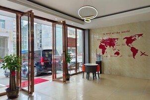 Um saguão de hotel com um mapa-múndi na parede, um balcão de recepção e uma entrada por porta de vidro.