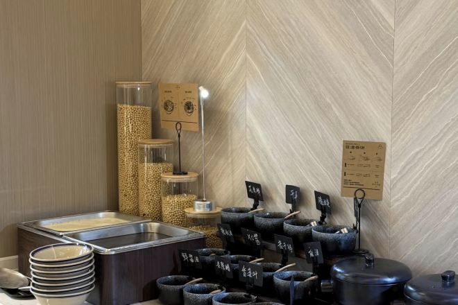 Disposição de buffet com vários recipientes de comida e um quadro de cardápio.