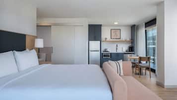 Quarto de hotel moderno com uma cama grande, um sofá, uma cozinha e uma mesa de jantar.