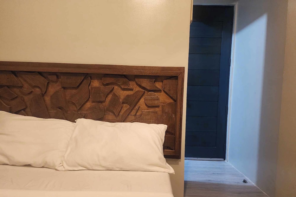 Uma cama com cabeceira de madeira e roupa de cama branca.