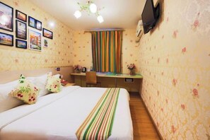 Quarto de hotel com cama, escrivaninha e televisão.