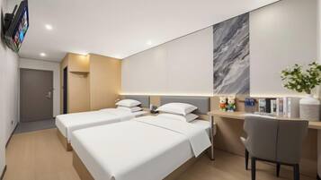 Quarto de hotel com duas camas, uma escrivaninha, uma cadeira, televisão e um espelho grande.