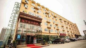 Um hotel com vários andares, entrada destacada, tapete vermelho que leva à porta e diversas varandas.
