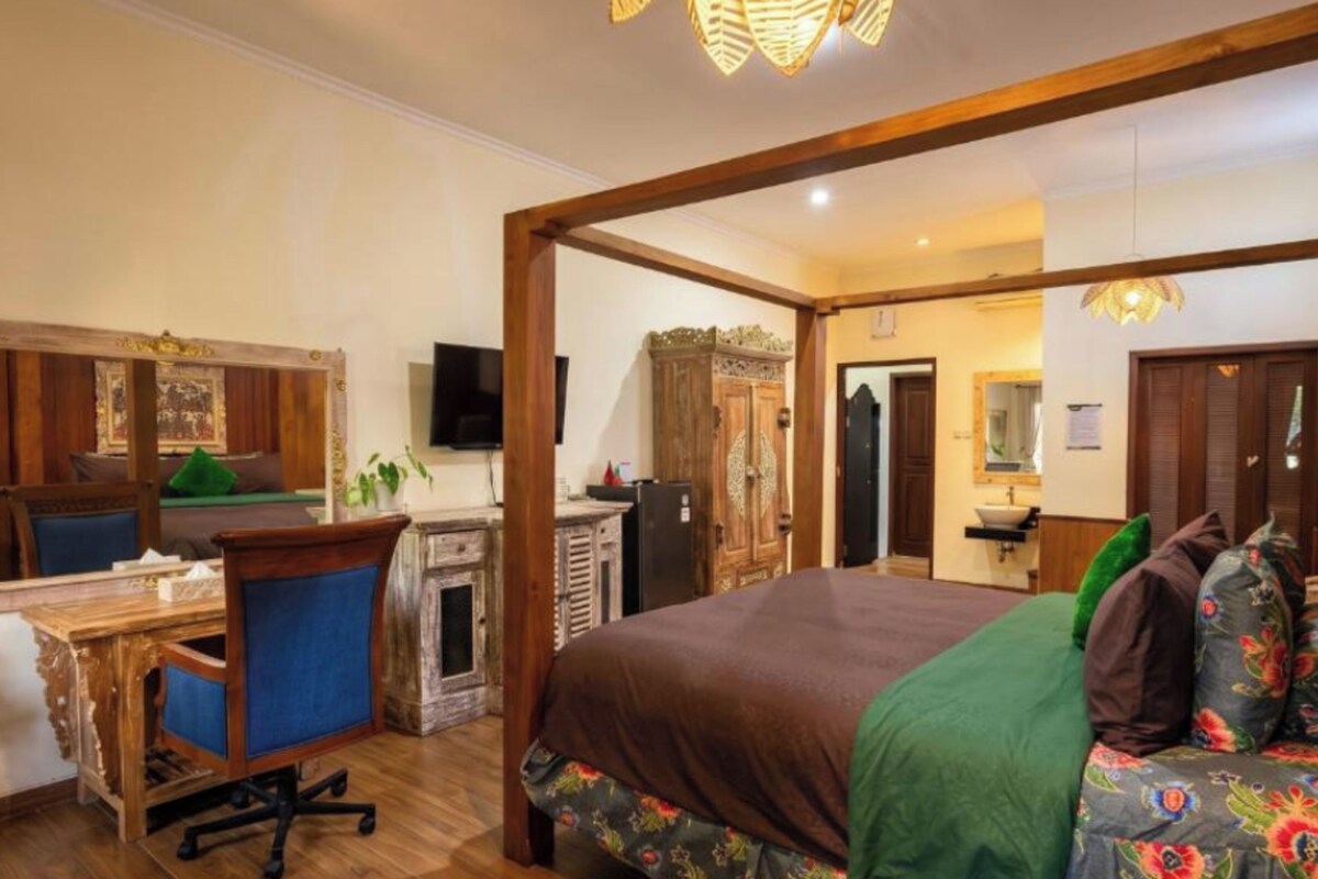 Quarto com cama de dossel, escrivaninha com cadeira, televisão e guarda-roupa.