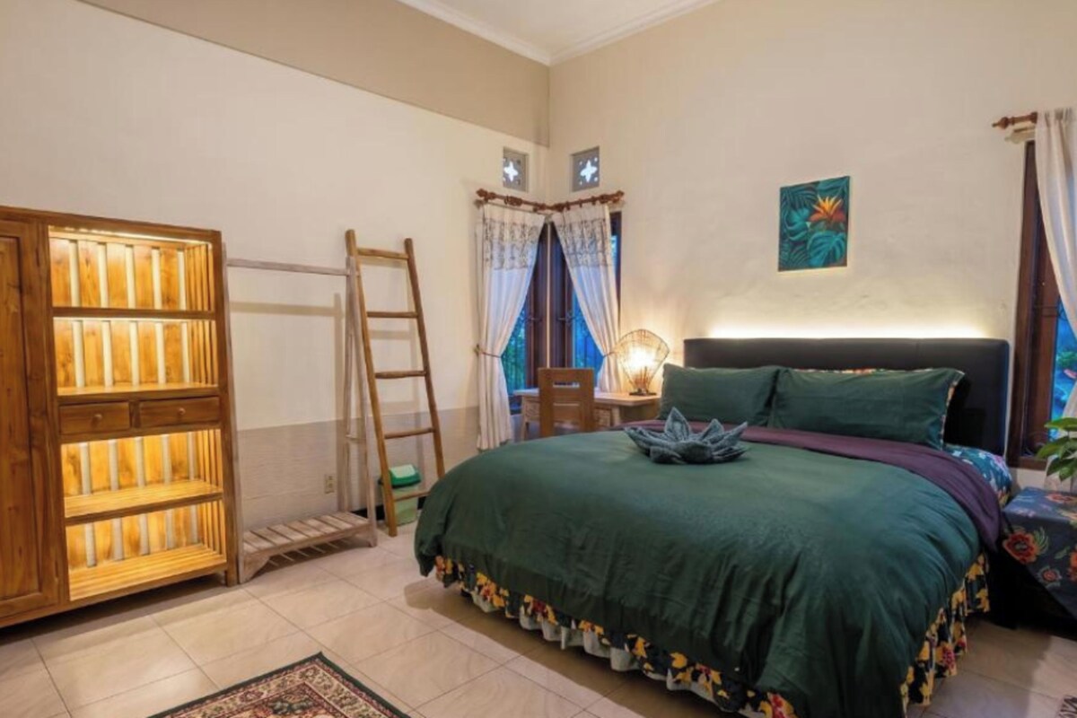 Quarto com cama, guarda-roupa, escada, mesa de cabeceira e um quadro na parede.