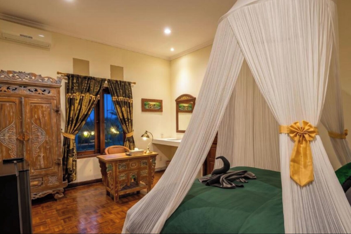 Quarto com cama de dossel, móveis de madeira, escrivaninha e janela com cortinas.