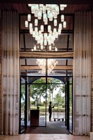 Interior moderno com uma grande porta de vidro que dá para o exterior, uma pessoa ao lado de um carrinho e um lustre singular.