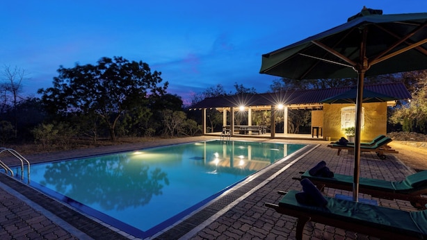 Piscina com área de estar coberta e espreguiçadeiras.