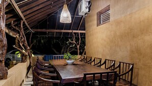 Uma sala de jantar com uma mesa de madeira comprida, várias cadeiras e um lustre.