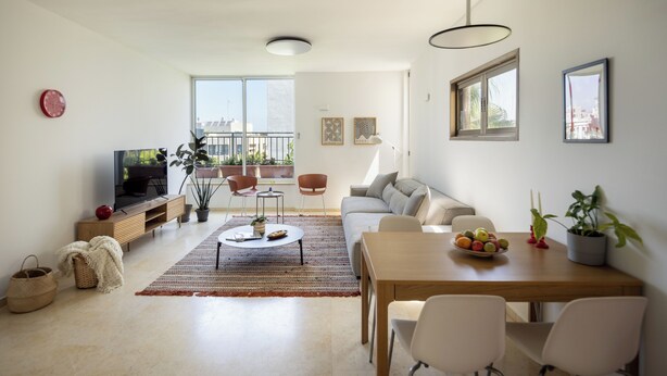 Uma sala de estar moderna com sofá, mesa de centro, televisão e área de jantar.