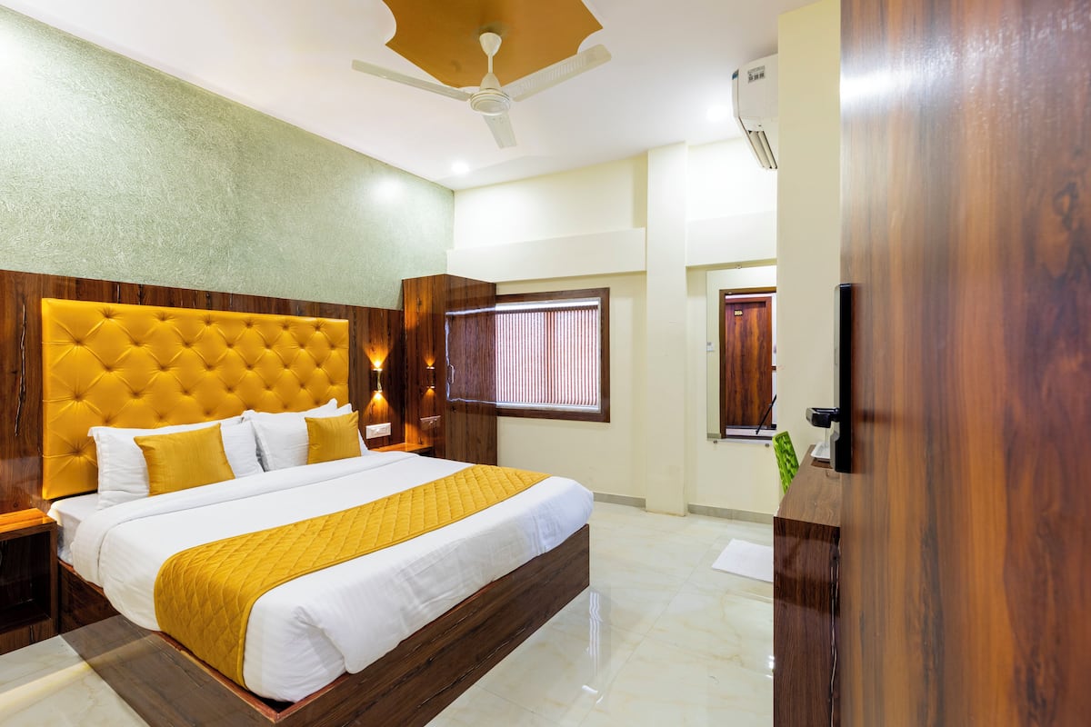 Quarto de hotel com uma cama grande, cabeceira de madeira, mesas de cabeceira e um ventilador de teto.