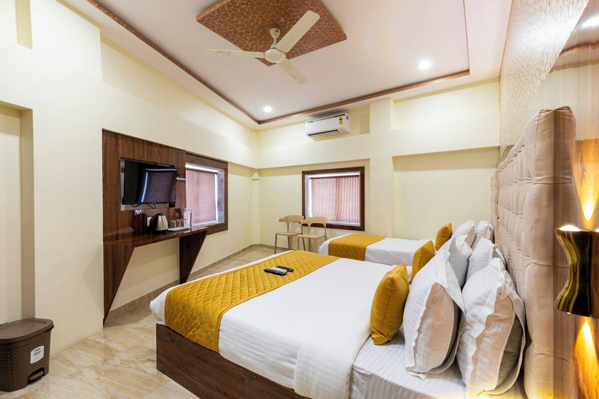 Quarto de hotel com cama, escrivaninha com televisão e uma cadeira.
