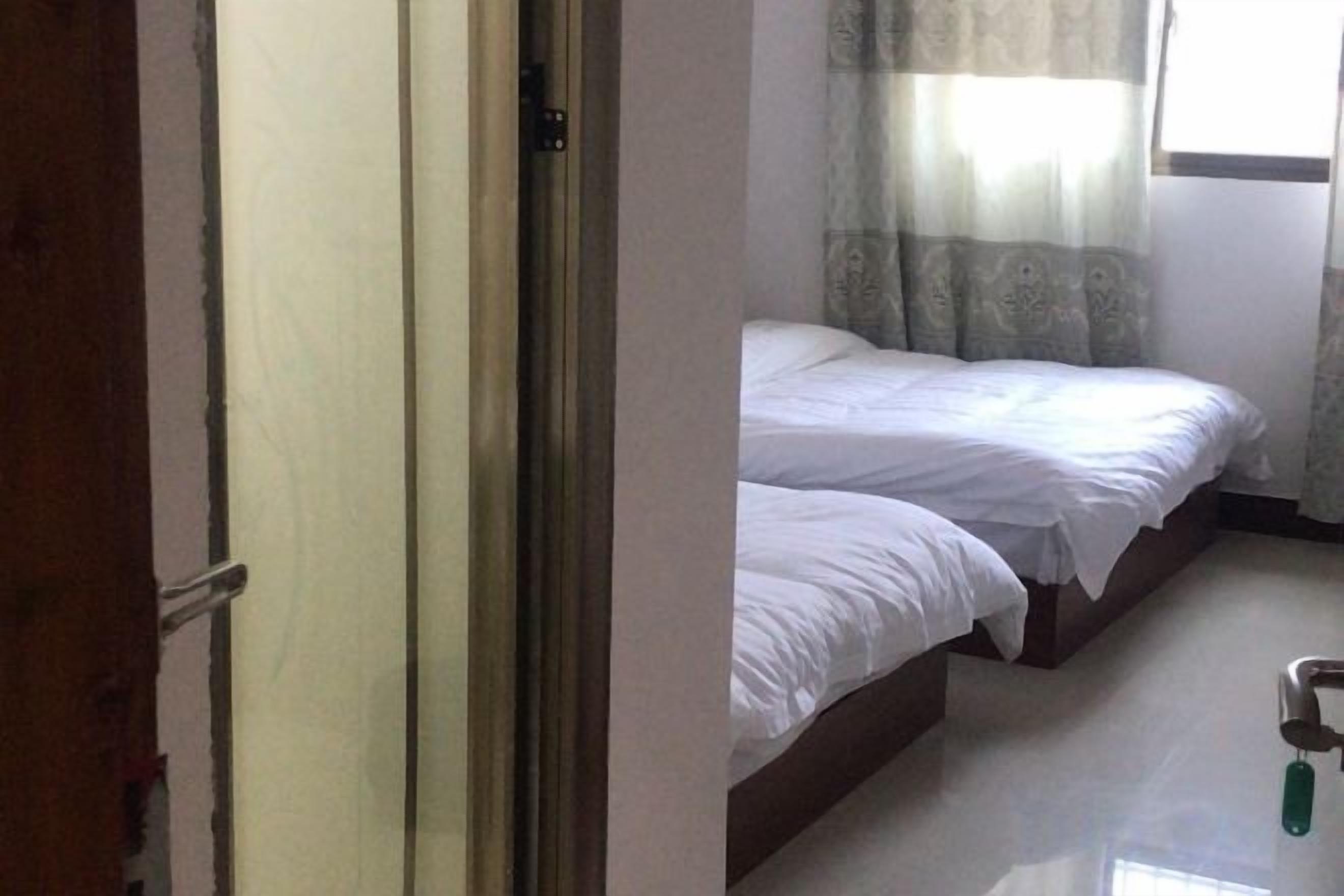 Um quarto com uma cama, uma porta e uma janela com cortinas.