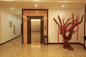 Um elevador, uma área de recepção e uma escultura.