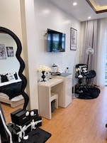 Quarto moderno com cama, escrivaninha, cadeira, televisão e espelho.
