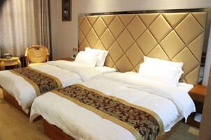 Quarto de hotel com duas camas, cabeceira, mesa de cabeceira e uma cadeira.