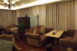 Quarto de hotel com um sofá, uma mesinha e uma planta decorativa.