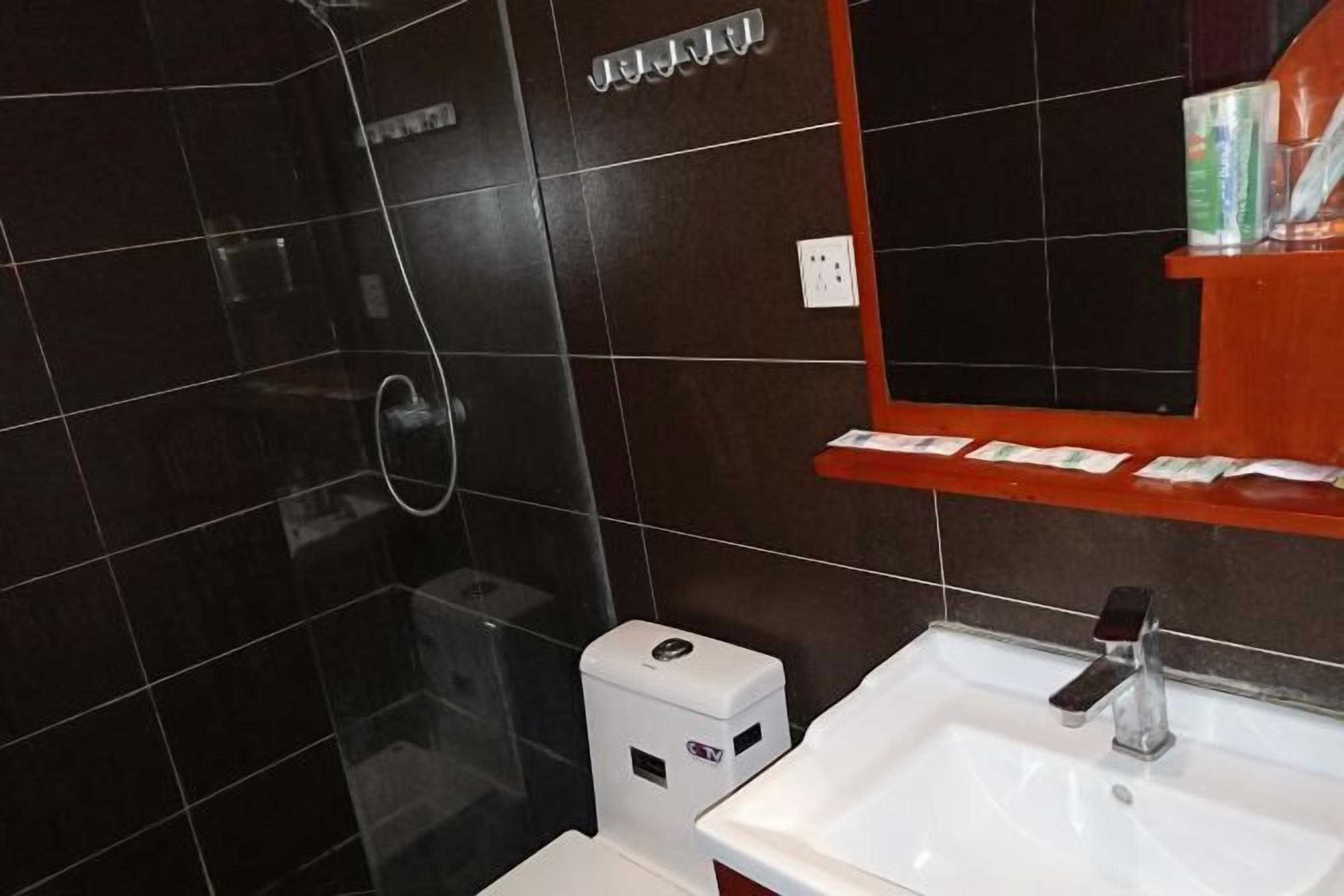 Casa de banho com cabine de duche em vidro, uma pia branca com torneira moderna e um armário com produtos de higiene pessoal.