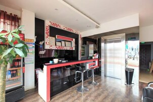 Uma área de bar moderna com balcão, banquetas e um espelho grande.