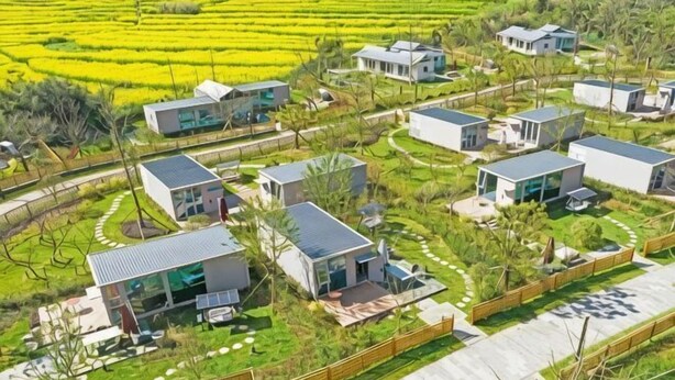 Um bairro residencial com casas modernas, um gramado bem cuidado e uma vista ampla da paisagem ao redor.