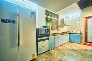 Cozinha compacta com geladeira, micro-ondas, fogão e armários.