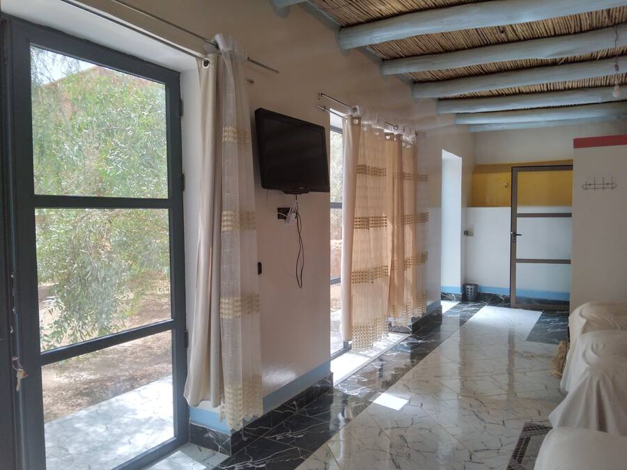 Um corredor de hotel com uma janela grande, uma televisão de tela plana na parede e uma porta com esquema de cores amarelo e branco.