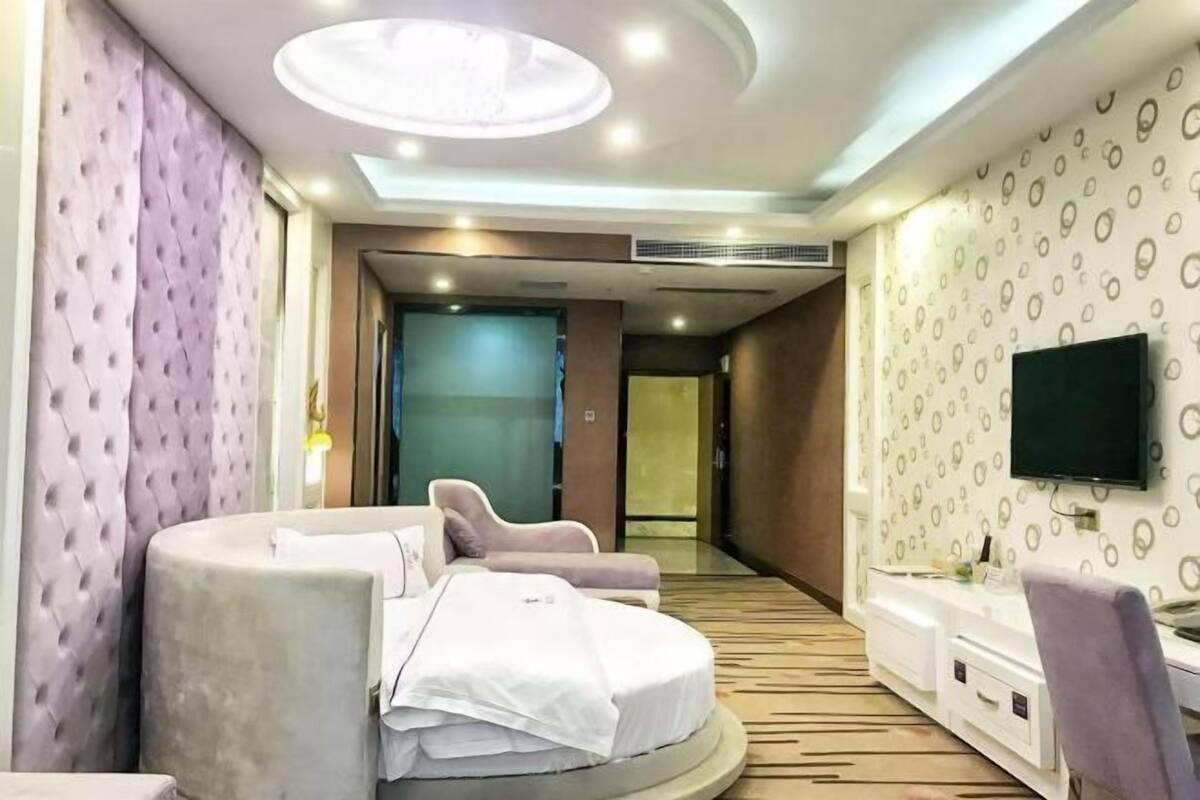 Quarto de hotel com cama, área de estar, televisão e banheiro.