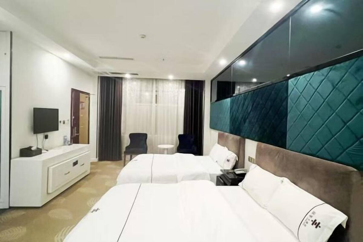 Quarto de hotel com duas camas, televisão, escrivaninha e cadeira.