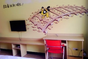 Quarto com mural na parede, televisão, escrivaninha e uma cadeira vermelha.