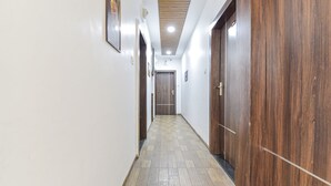 Um corredor com portas de madeira, piso de azulejos e teto com iluminação embutida.