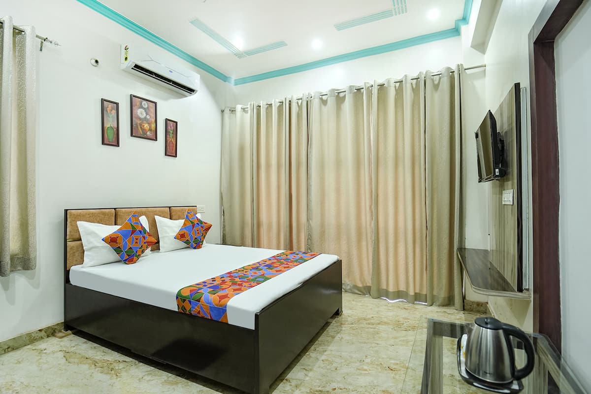 Quarto de hotel com cama, cortinas, televisão e máquina de café.