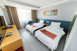 Quarto de hotel com duas camas, uma escrivaninha, uma cadeira e uma pequena mesa.