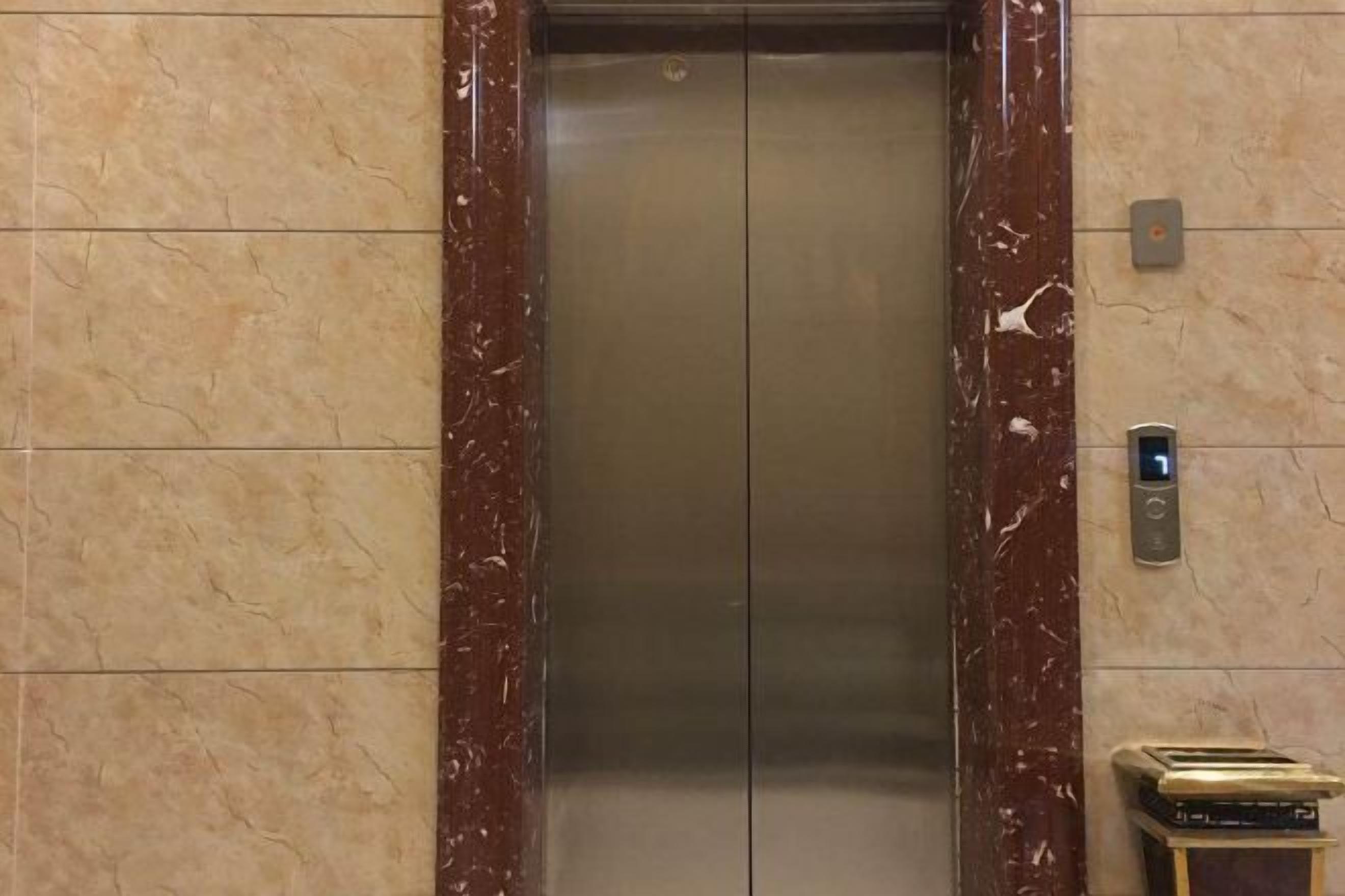 Um elevador com estrutura de mármore, painel de controle e visor digital.