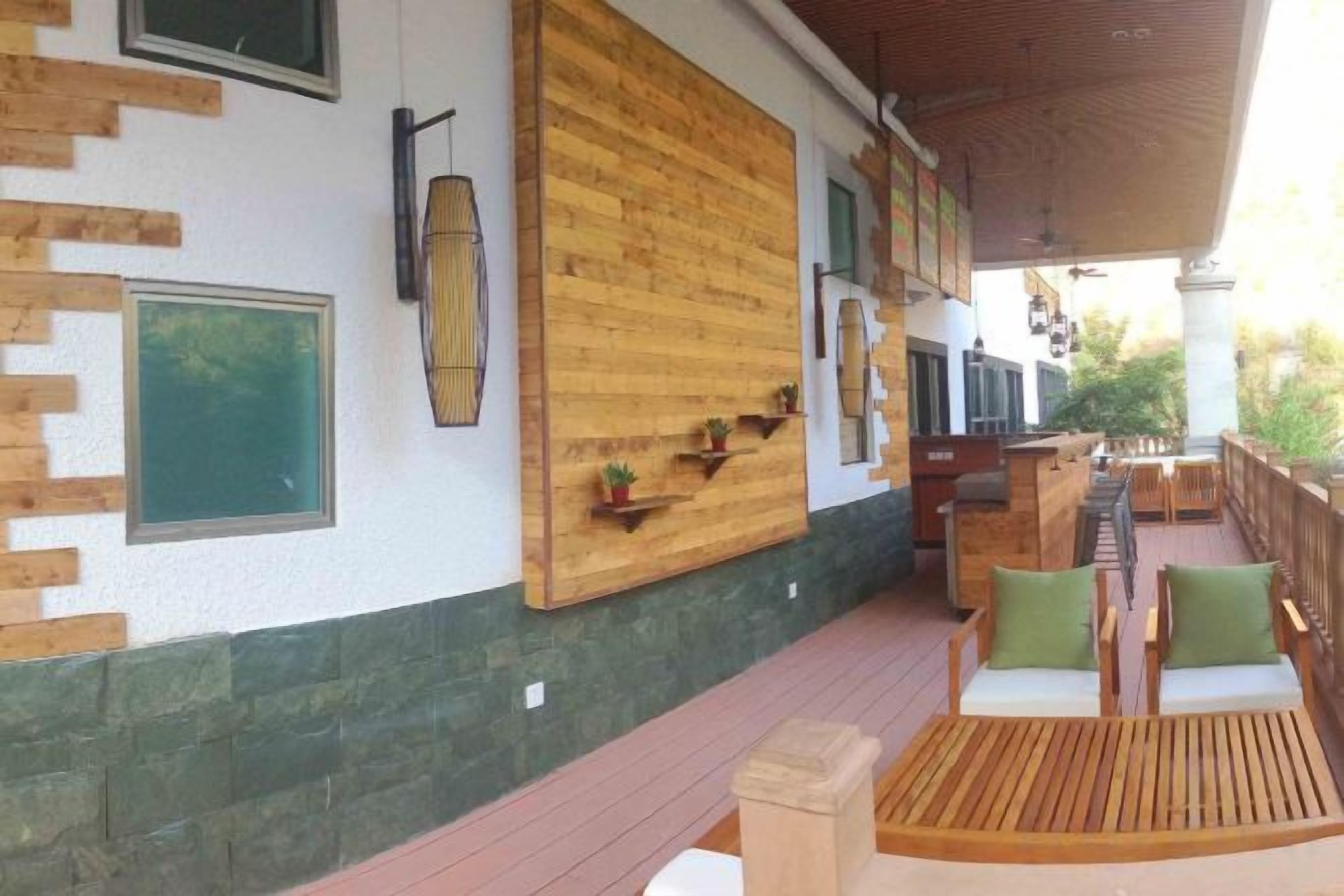 Um deck de madeira com área de estar externa, bar e uma parede de pedra com prateleiras.