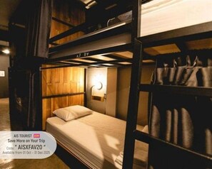 Quarto com beliche, cabeceira de madeira, mesa de cabeceira com luminária e mala no chão.
