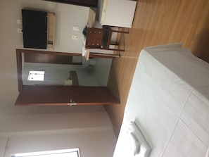 Um quarto com um armário de madeira, uma cama branca e uma janela.