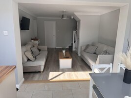 Uma sala de estar moderna com dois sofás, uma mesa de centro e uma TV fixada na parede.