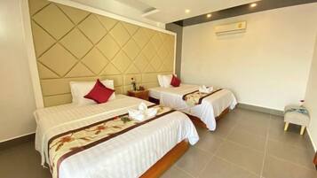 Quarto de hotel com duas camas, uma mesa pequena e cabeceira.