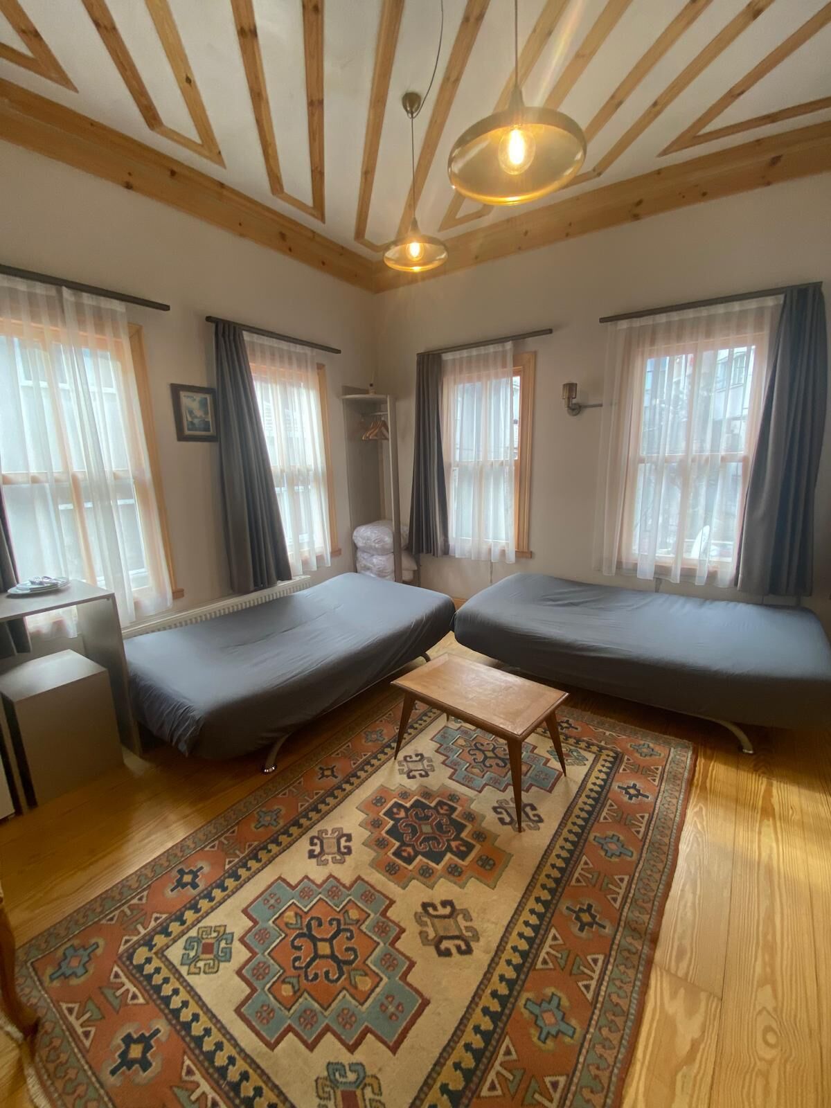 Um quarto aconchegante com duas camas, uma mesa pequena e um tapete estampado.
